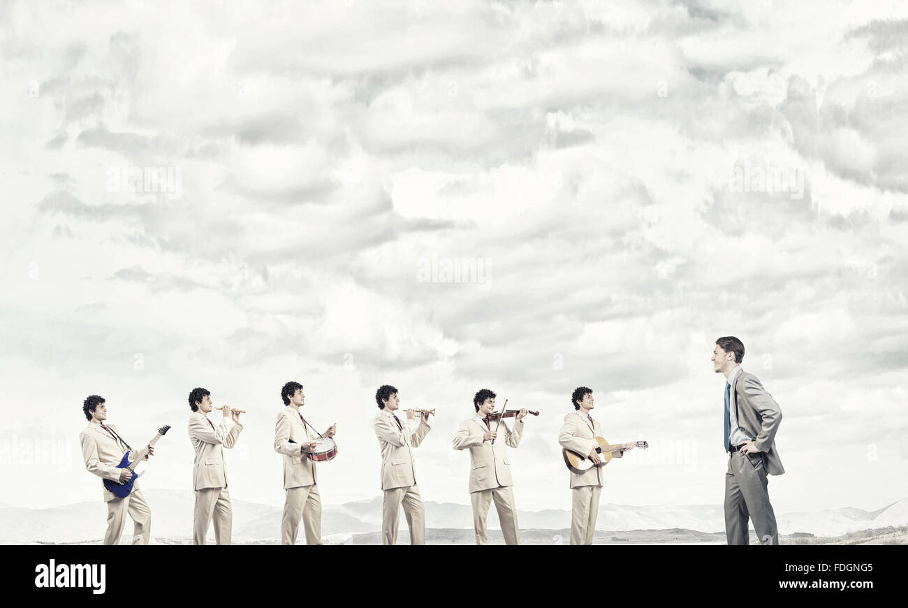 Man orchestra in suit playing different music instruments Stock Photo ...