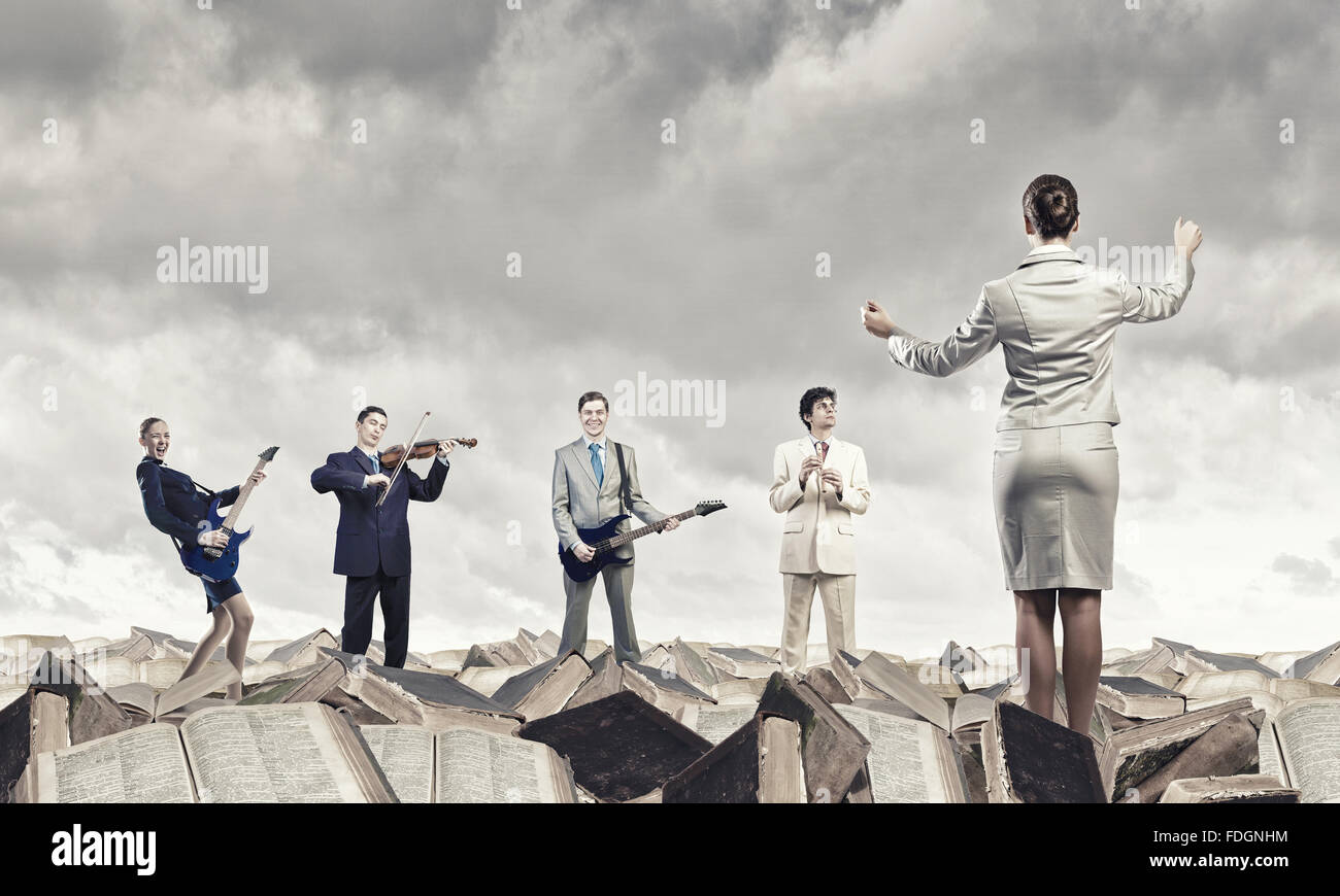 Conductor hand and business people playing different music instruments ...