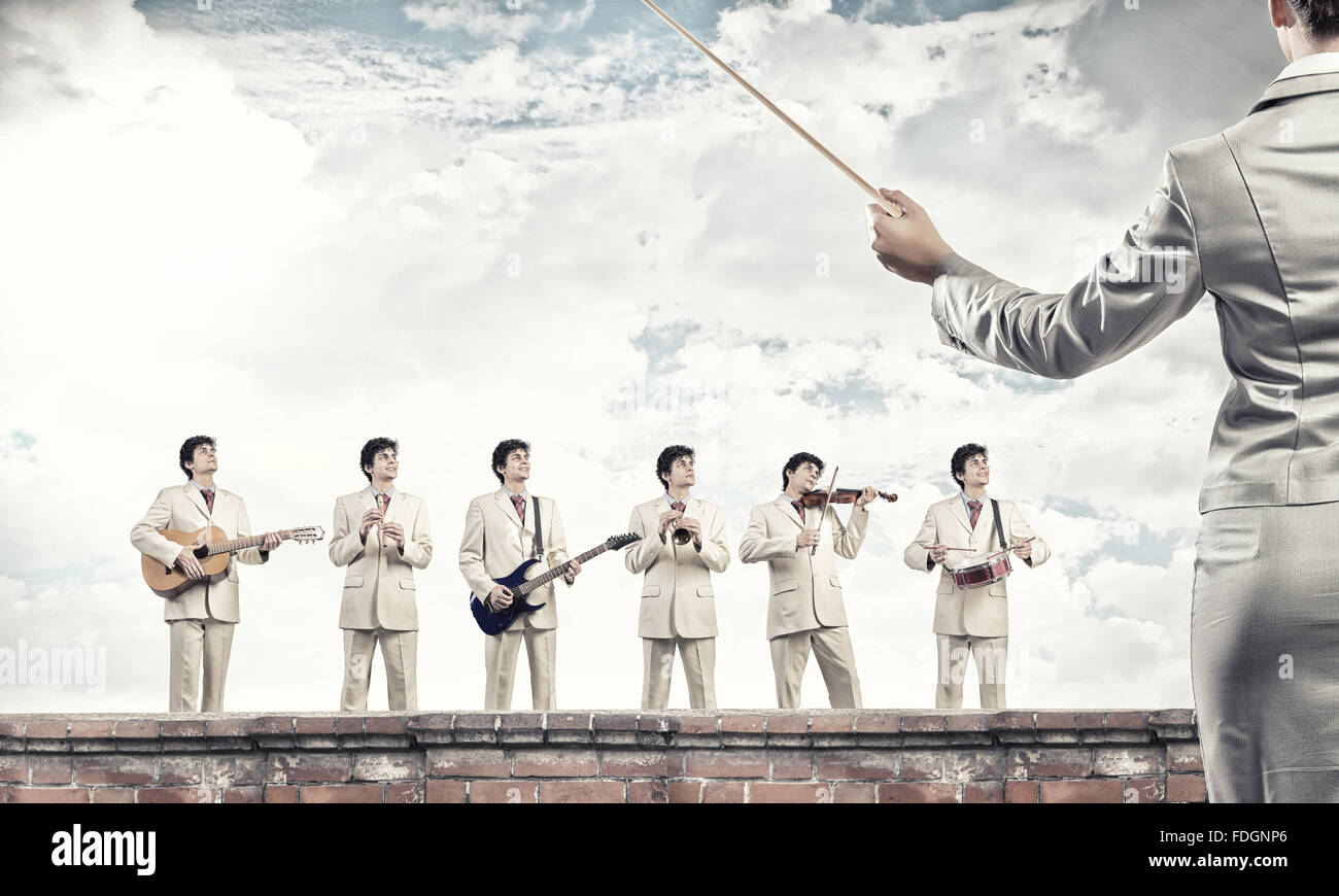 Man orchestra playing different music instruments and woman leader ...