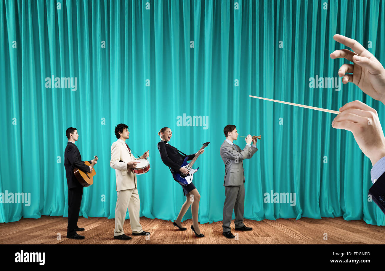 Conductor hand and business people playing different music instruments ...