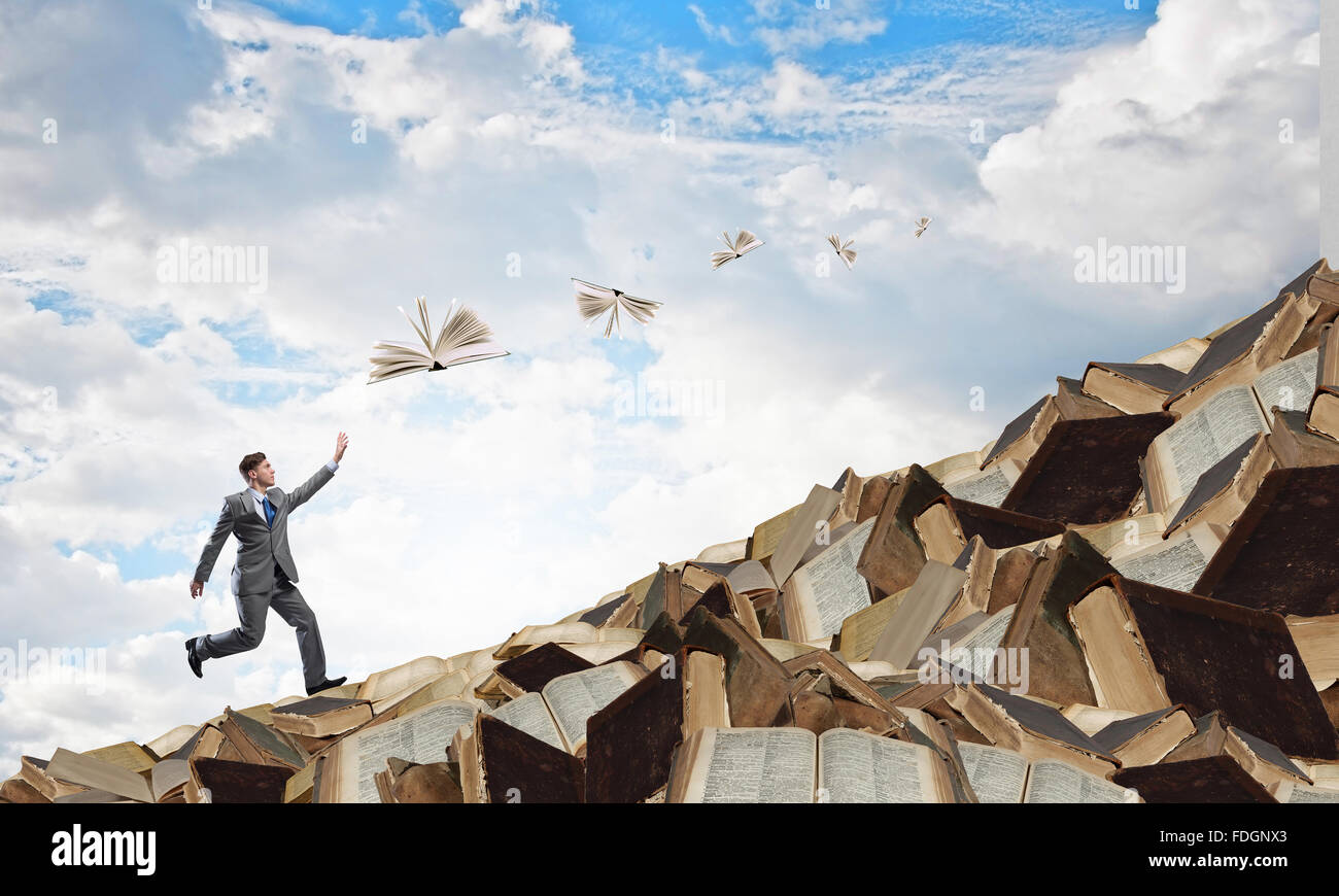Running young businessman trying to catch book Stock Photo - Alamy
