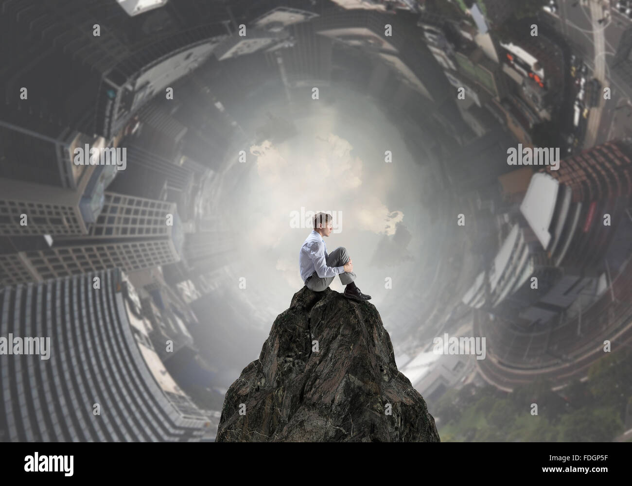 Young thoughtful businessman sitting alone on rock top Stock Photo - Alamy