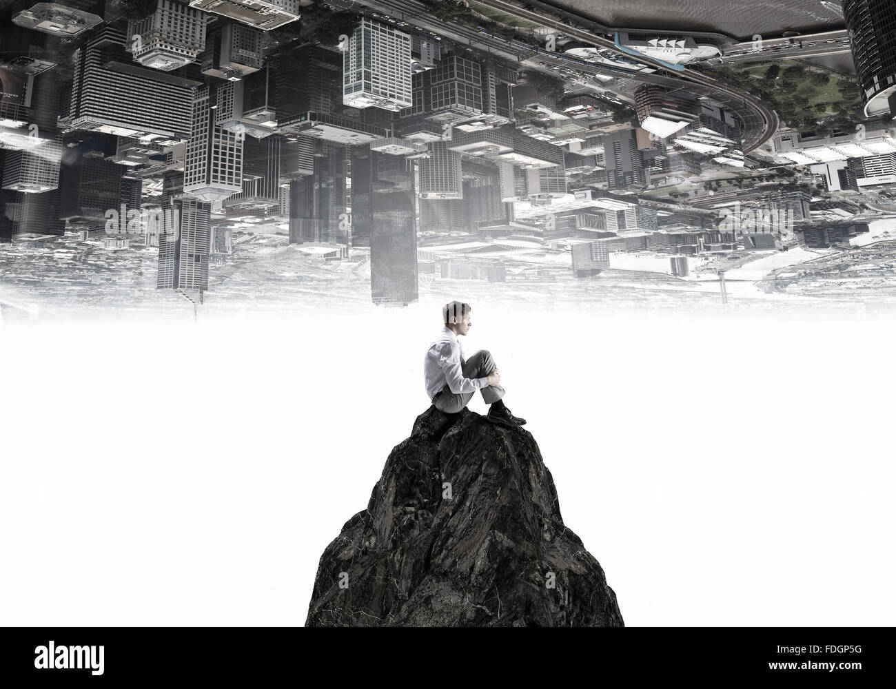 Young thoughtful businessman sitting alone on rock top Stock Photo - Alamy