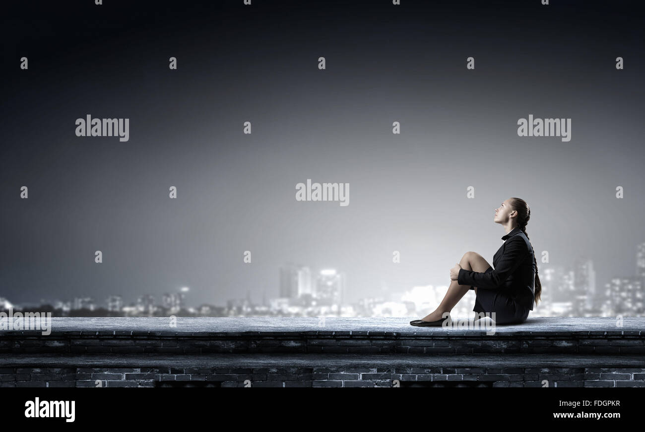 Bored young businesswoman sitting alone on roof Stock Photo - Alamy