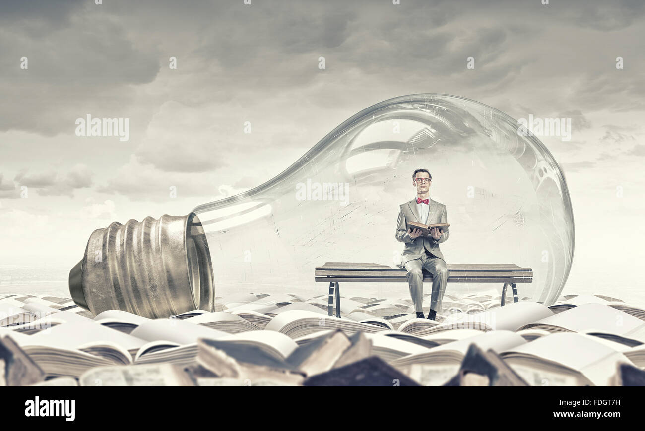 Young businessman inside of light bulb reading book Stock Photo - Alamy