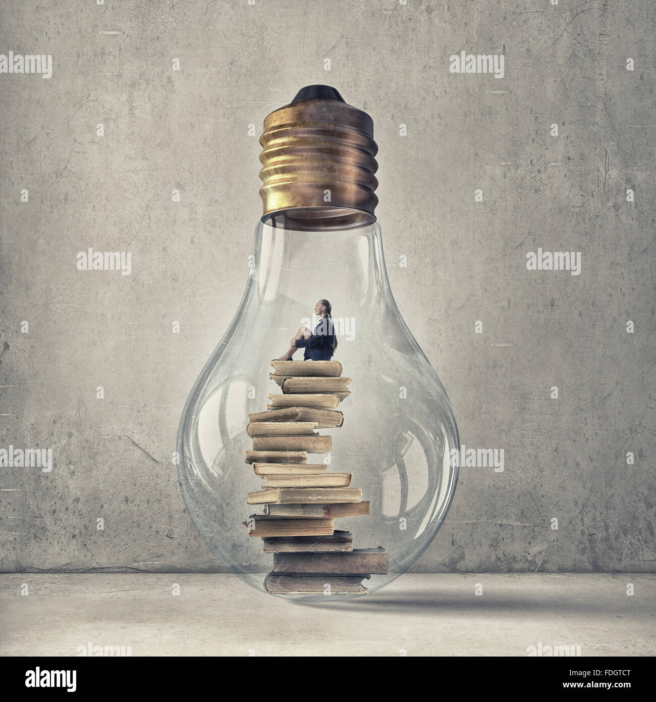 Young woman sitting om books stack inside of glass light bulb Stock ...