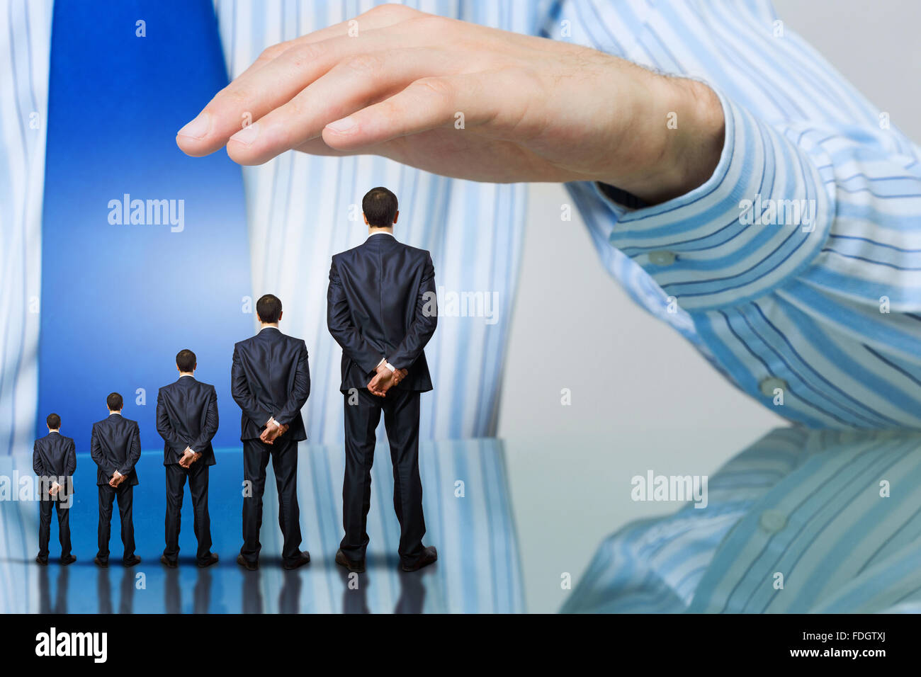 Male hand protecting business people of different size Stock Photo - Alamy