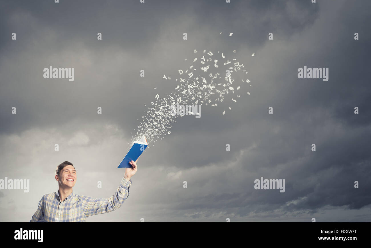 Young handsome man reaching hand with book and characters flying out ...