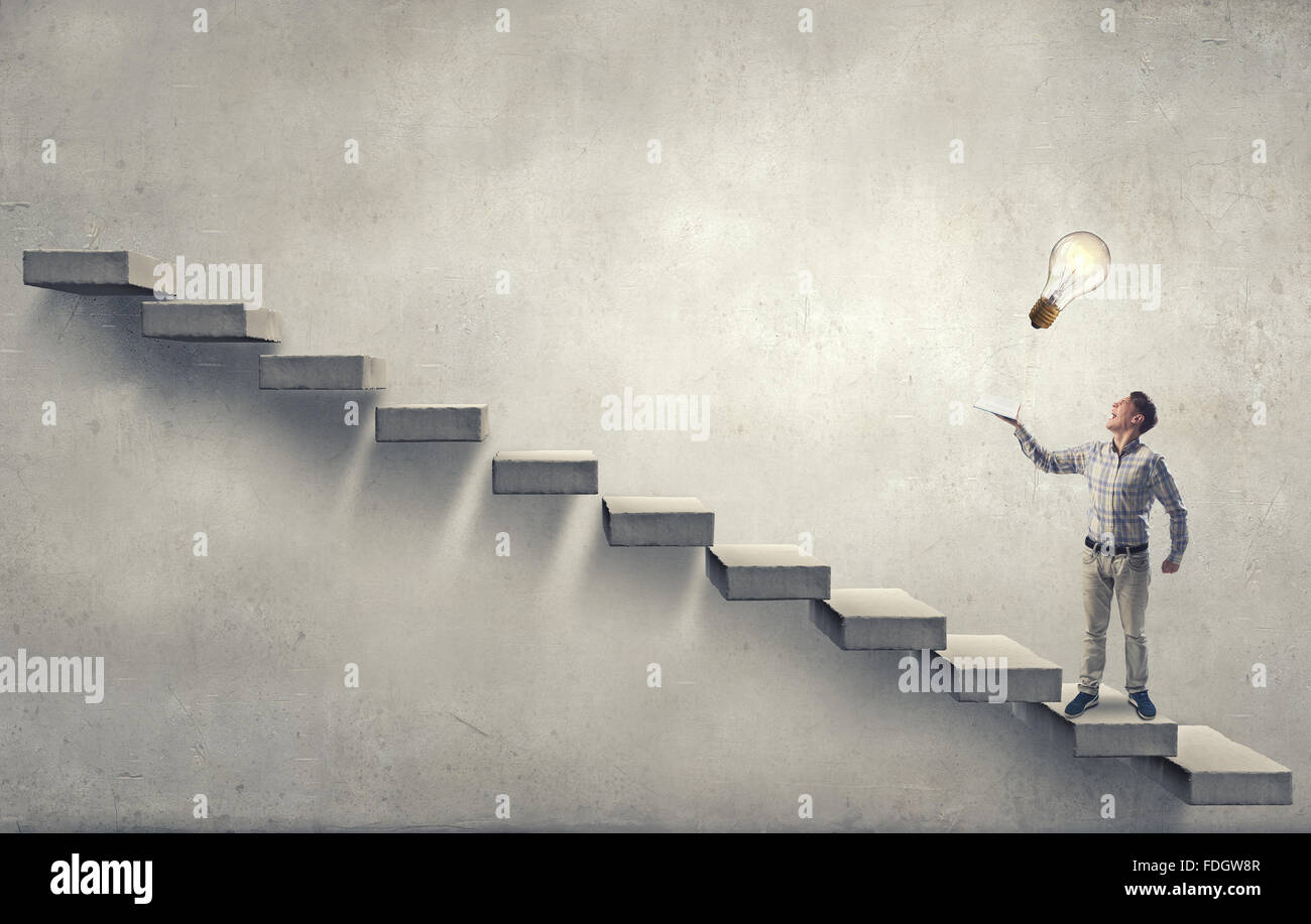 Young man running on steps reaching hand with book Stock Photo - Alamy