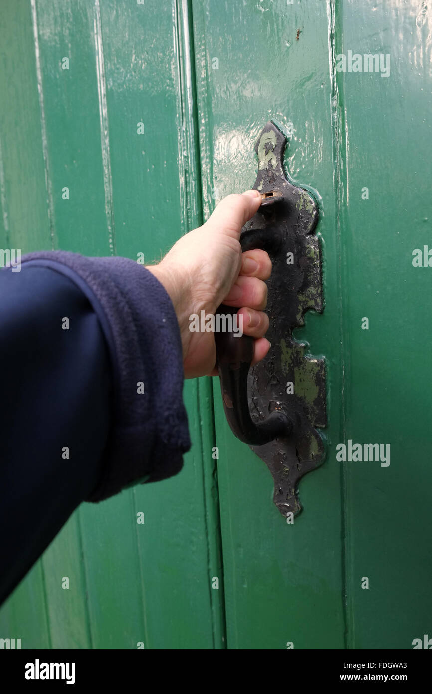 Pulling on the door, a man's hand on an old door latch Stock Photo - Alamy