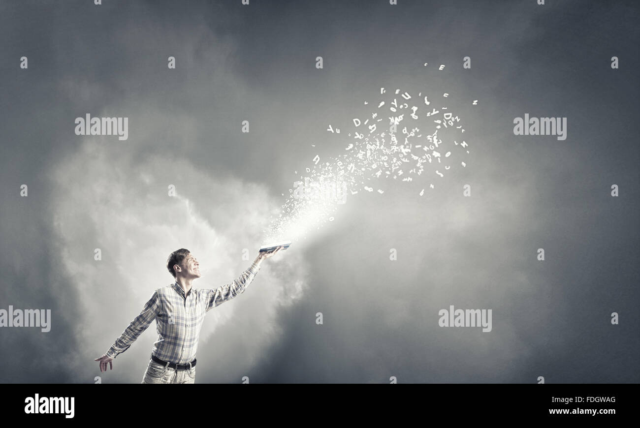 Young handsome man reaching hand with book and characters flying out ...