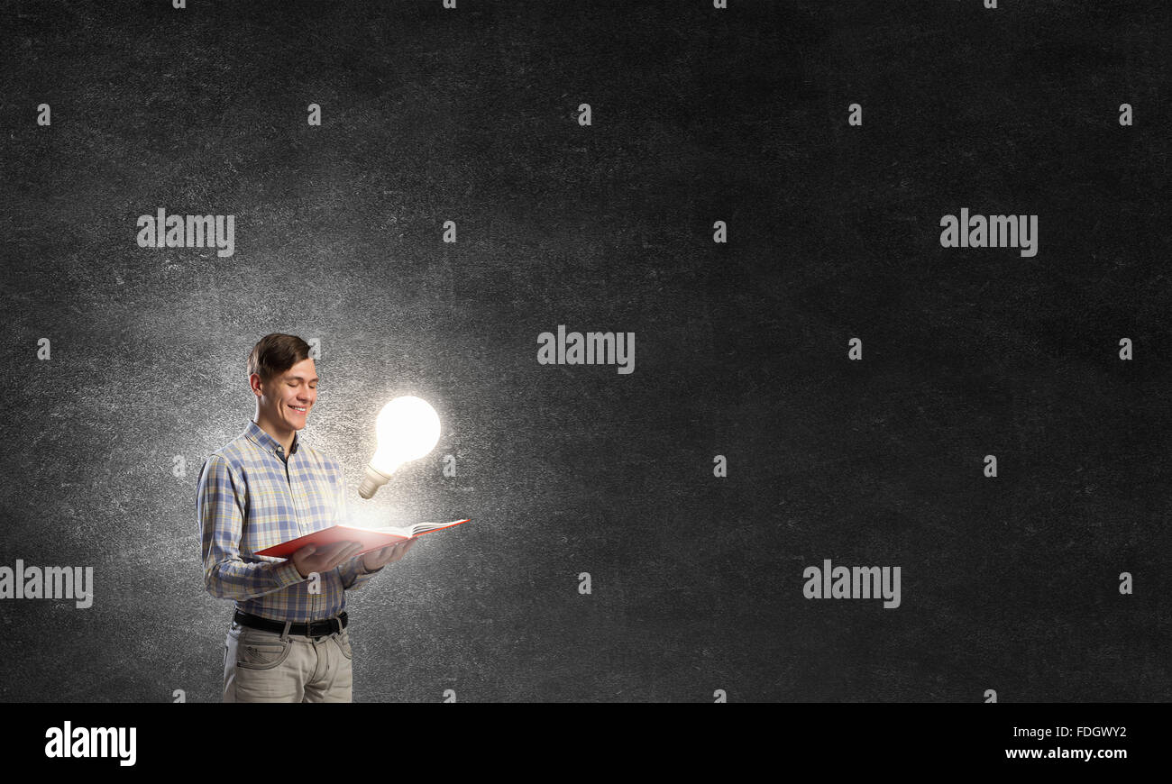 Young man holding opened book and glass glowing bulb on pages Stock ...