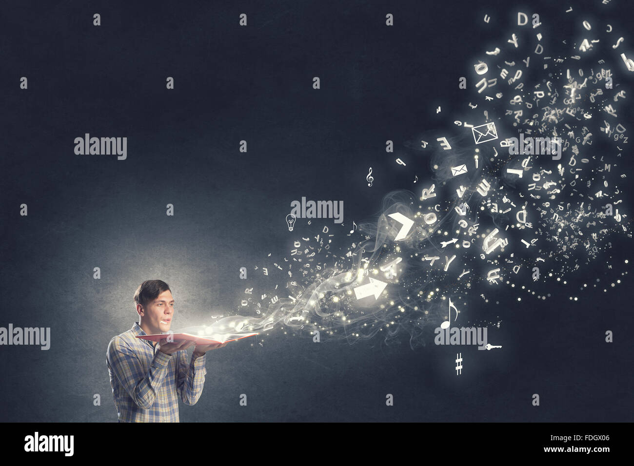 Young man with opened book in hands blowing on pages Stock Photo - Alamy