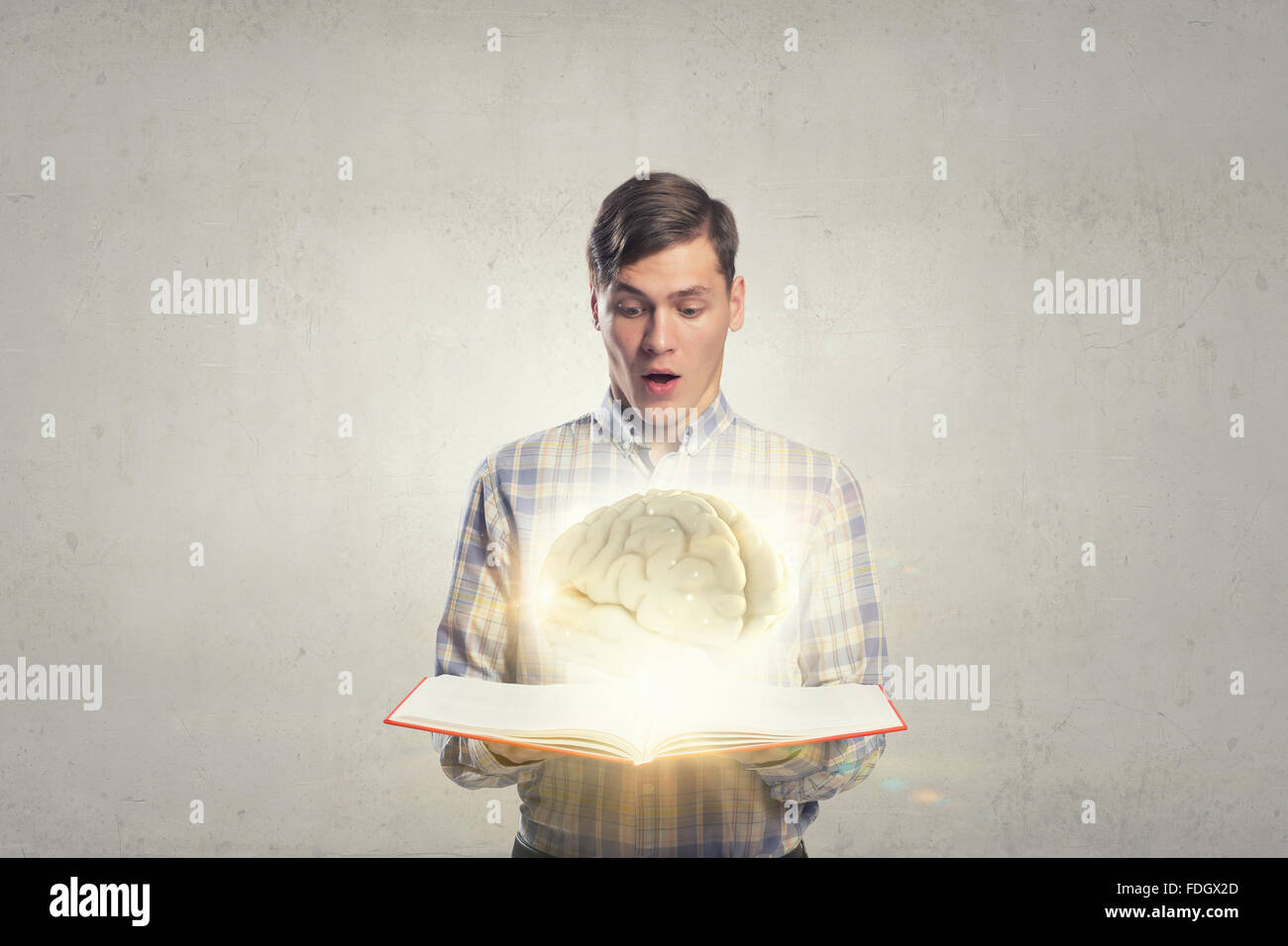 Shocked man holding opened book with brain picture Stock Photo - Alamy