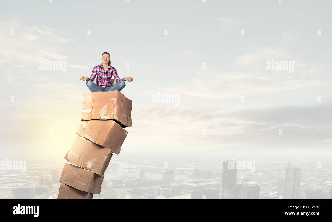 Smiling young woman sitting on carton boxes and meditating Stock Photo ...