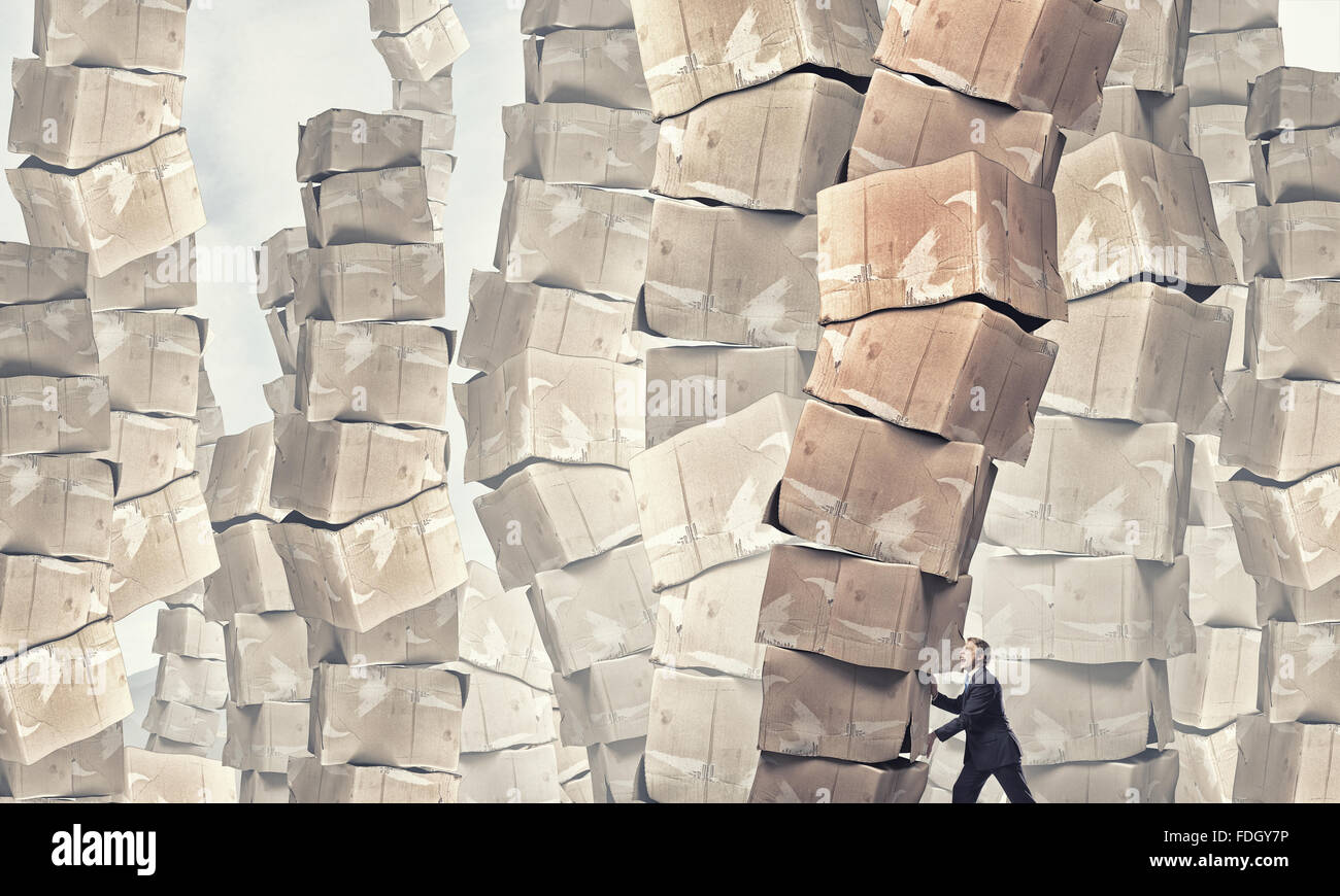 Young businessman making effort to move stack of carton boxes Stock ...