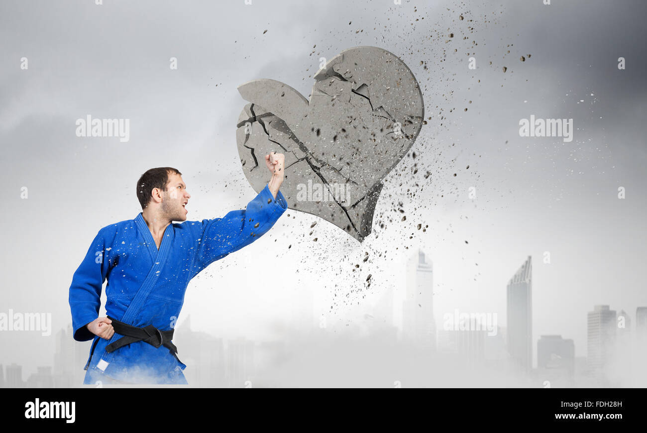 Young determined karate man breaking with hand concrete heart Stock ...