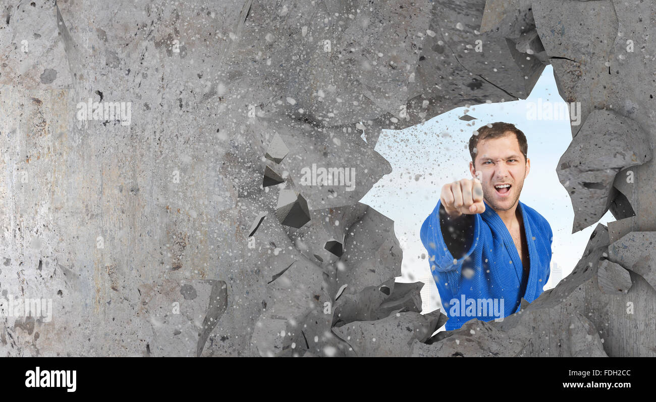 Young determined karate man breaking with hand concrete wall Stock ...