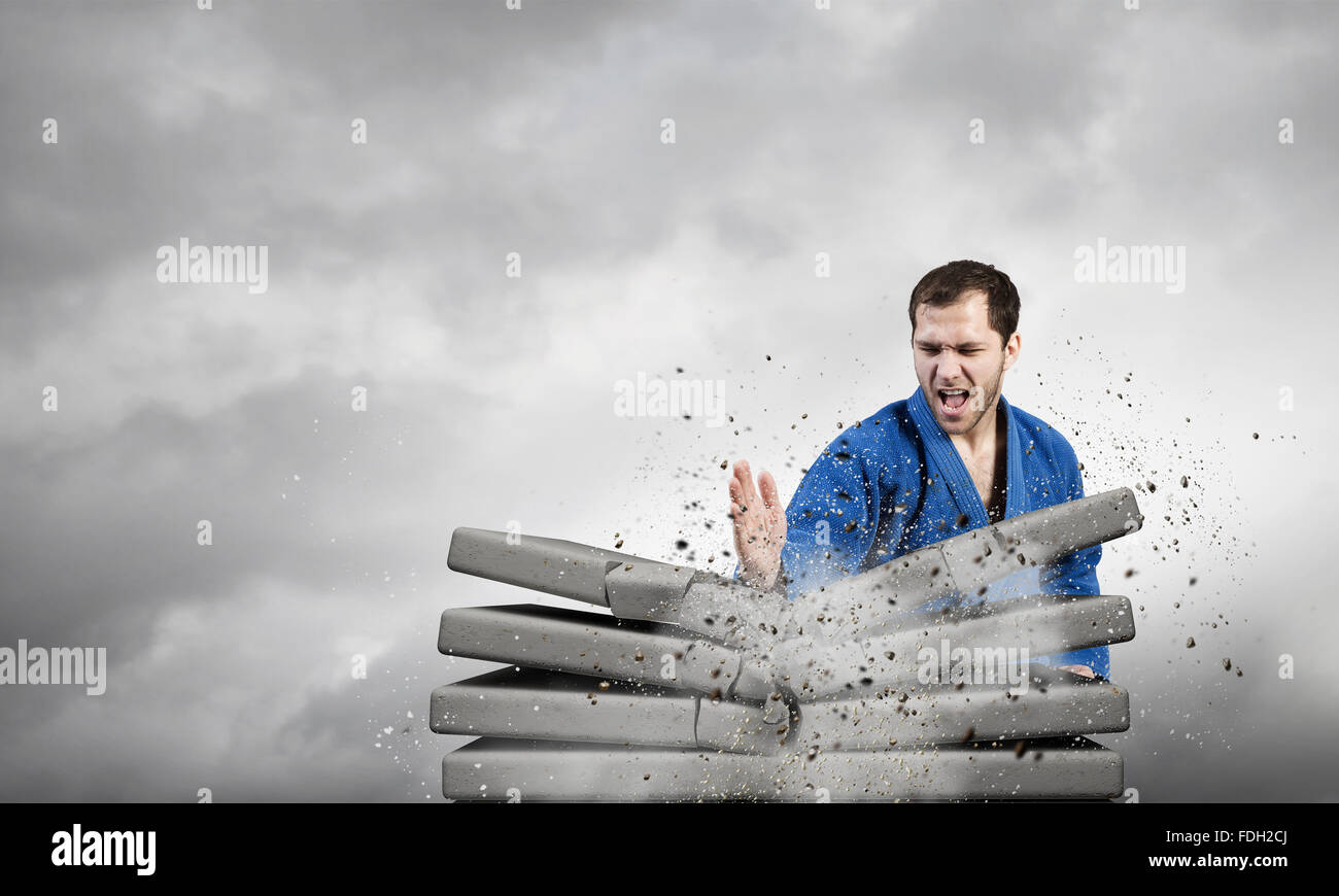 Young determined karate man breaking with hand concrete bricks Stock ...