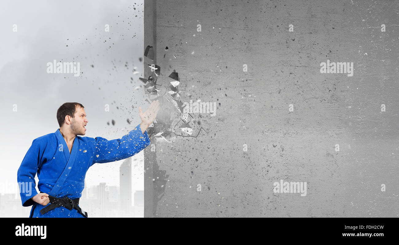 Young determined karate man breaking with hand concrete wall Stock ...