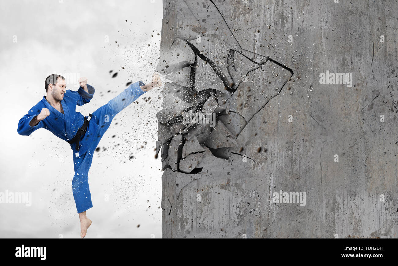 Young determined karate man breaking with leg concrete wall Stock Photo ...