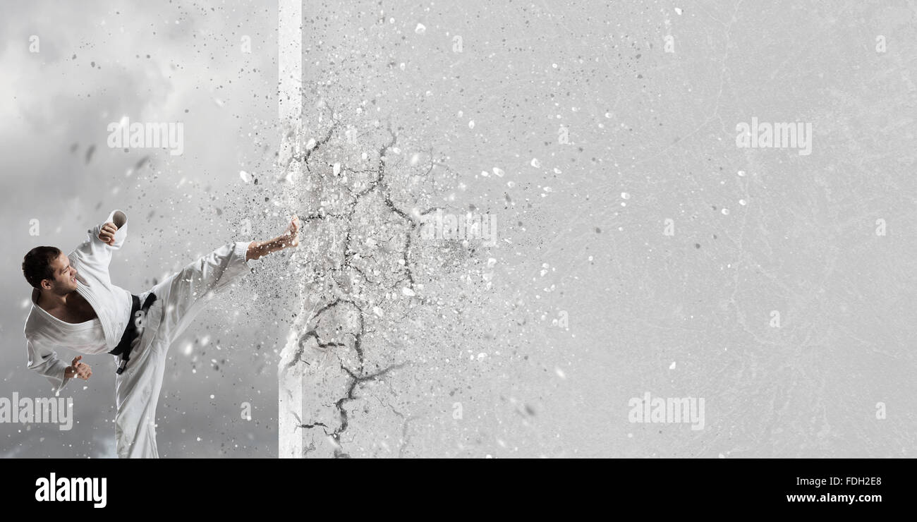 Young determined karate man breaking with leg concrete wall Stock Photo ...