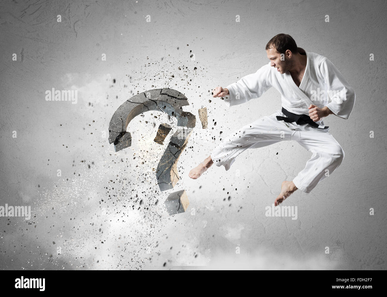 Young determined karate man breaking with leg concrete question sign ...