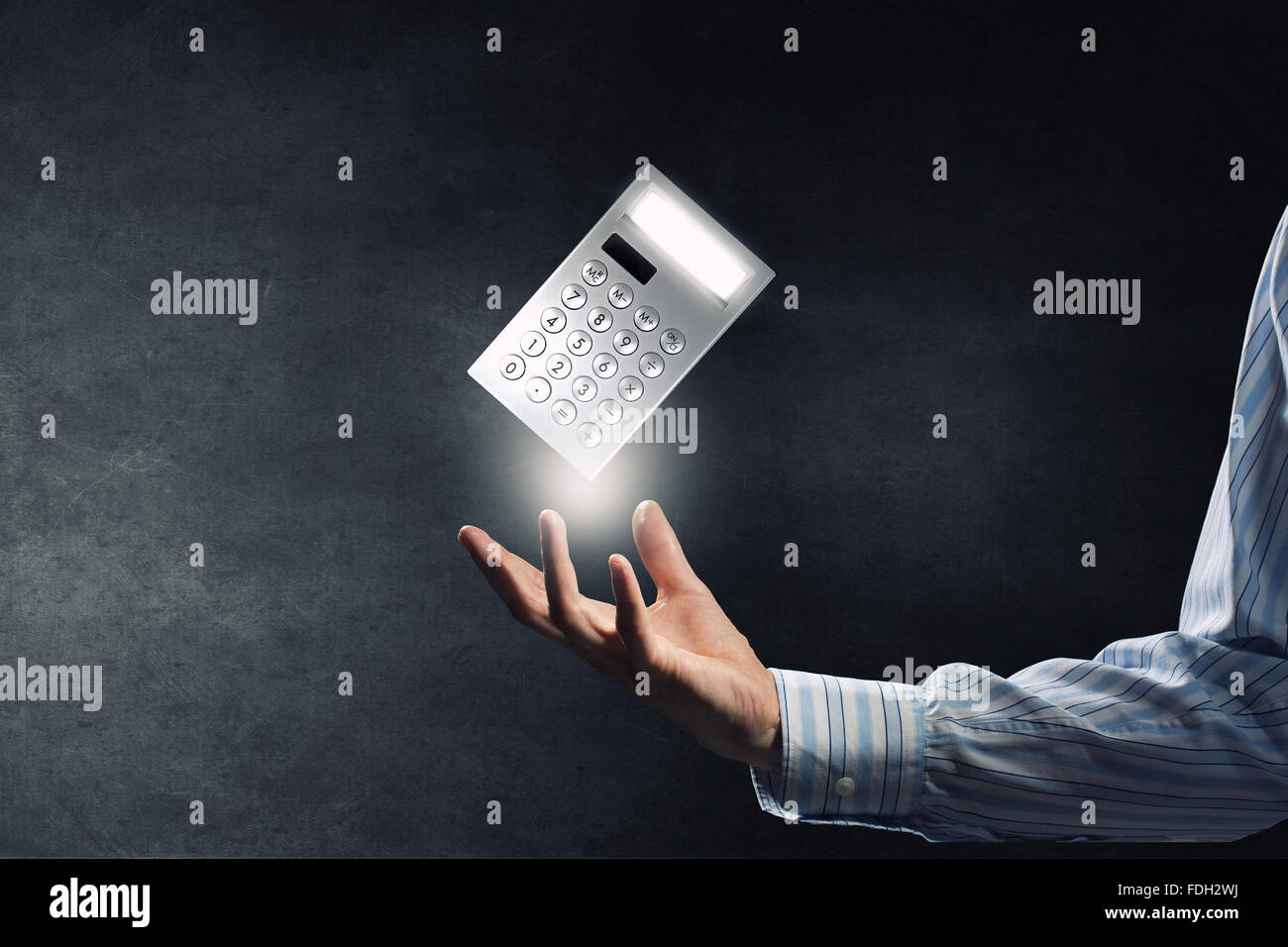 Man hand with calculator on dark background Stock Photo - Alamy