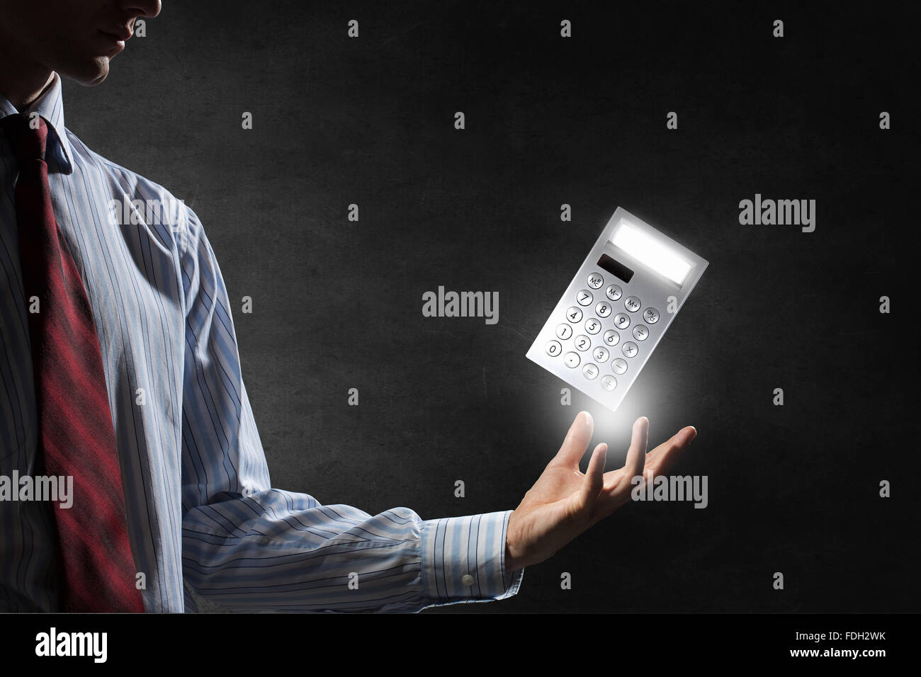 Man hand with calculator on dark background Stock Photo - Alamy