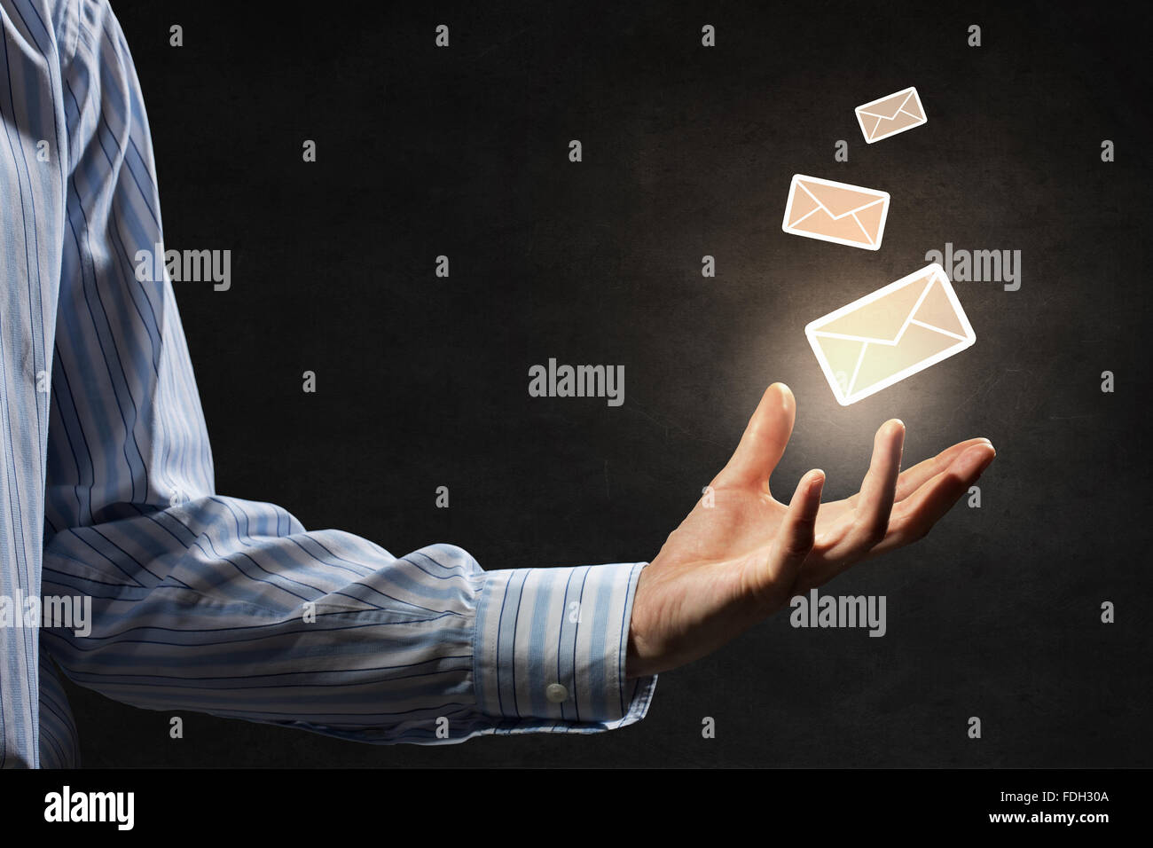 Businessman hand on dark background holding email symbols in palm Stock ...