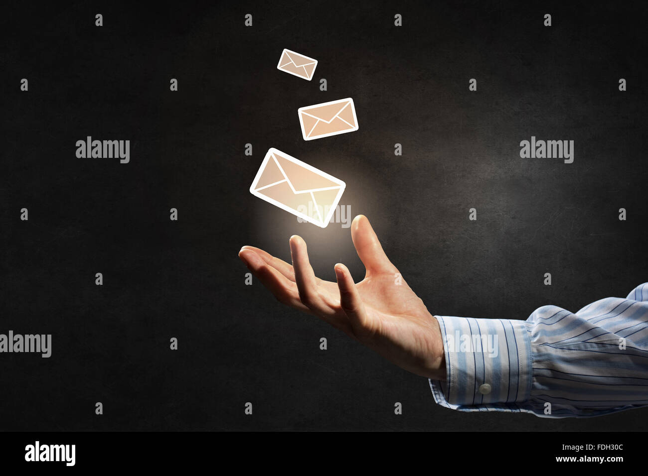 Businessman hand on dark background holding email symbols in palm Stock ...