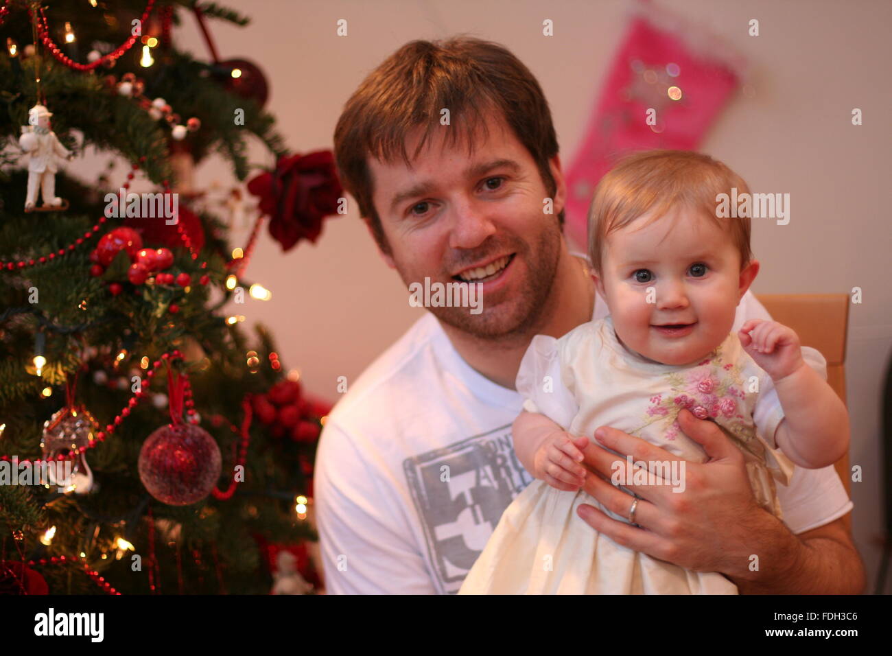 Daddy and baby daughter sitting real Christmas tree on babys first ...