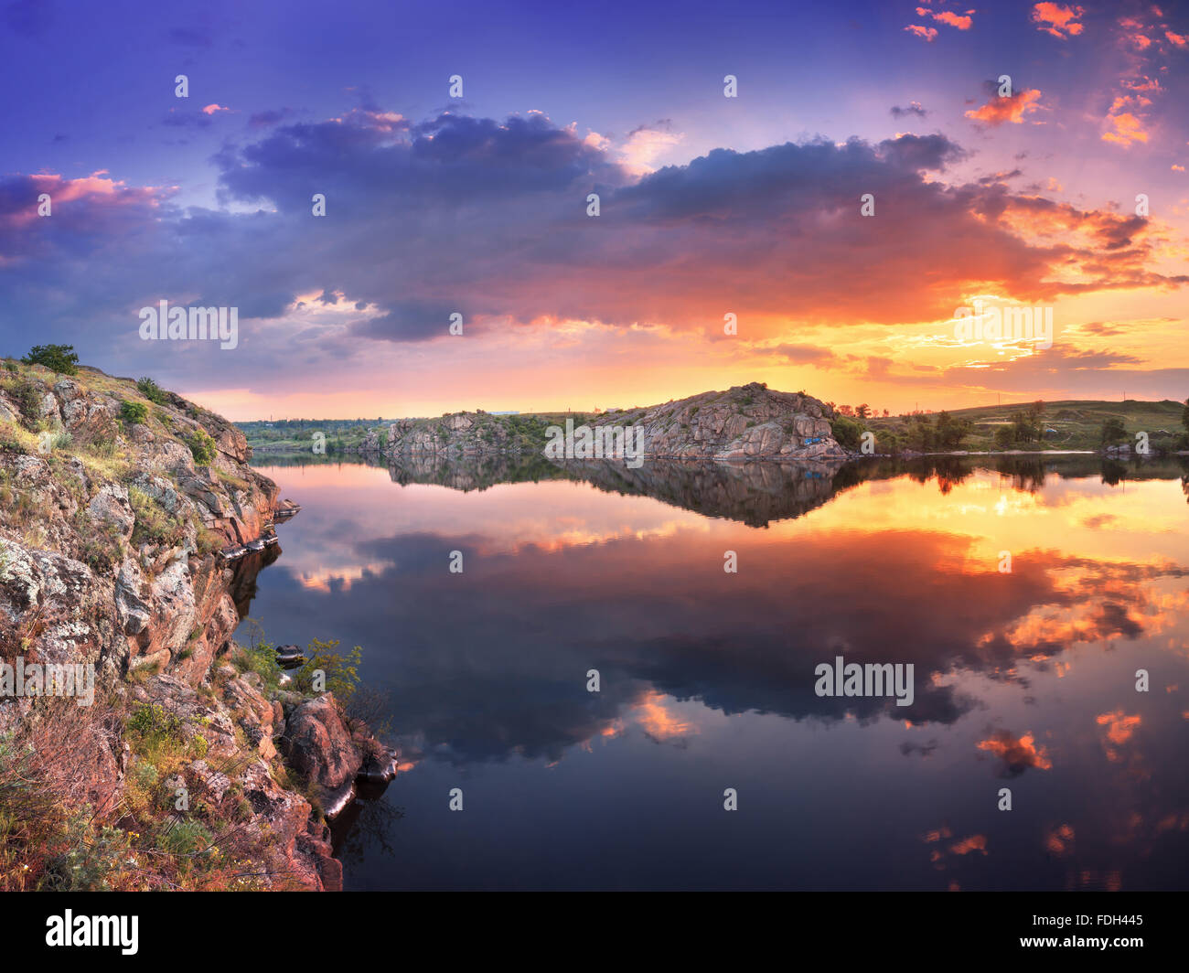 Beautiful summer sunset at the river with colorful sky, clouds, rocks ...