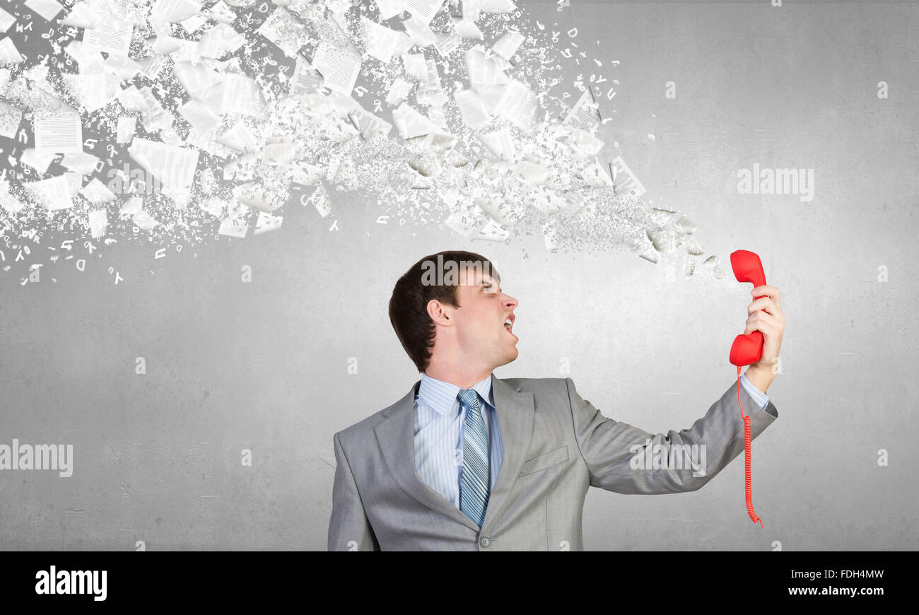 Angry businessman talking on red phone handset Stock Photo - Alamy