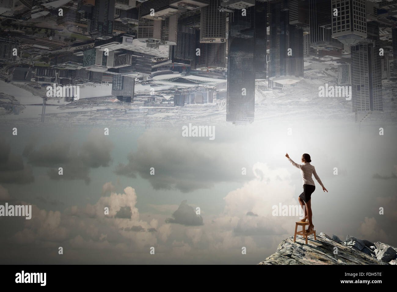 Businesswoman standing on chair and reaching hand to touch something ...