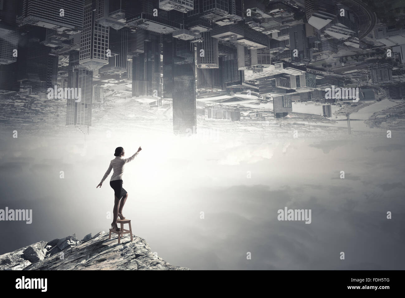 Businesswoman standing on chair and reaching hand to touch something ...