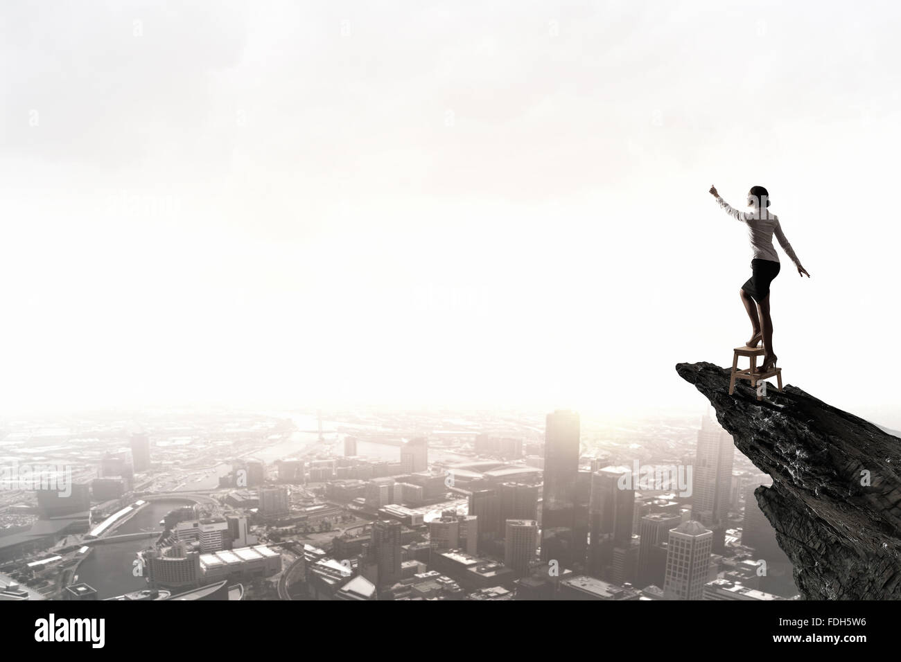 Businesswoman standing on chair and reaching hand to touch something ...