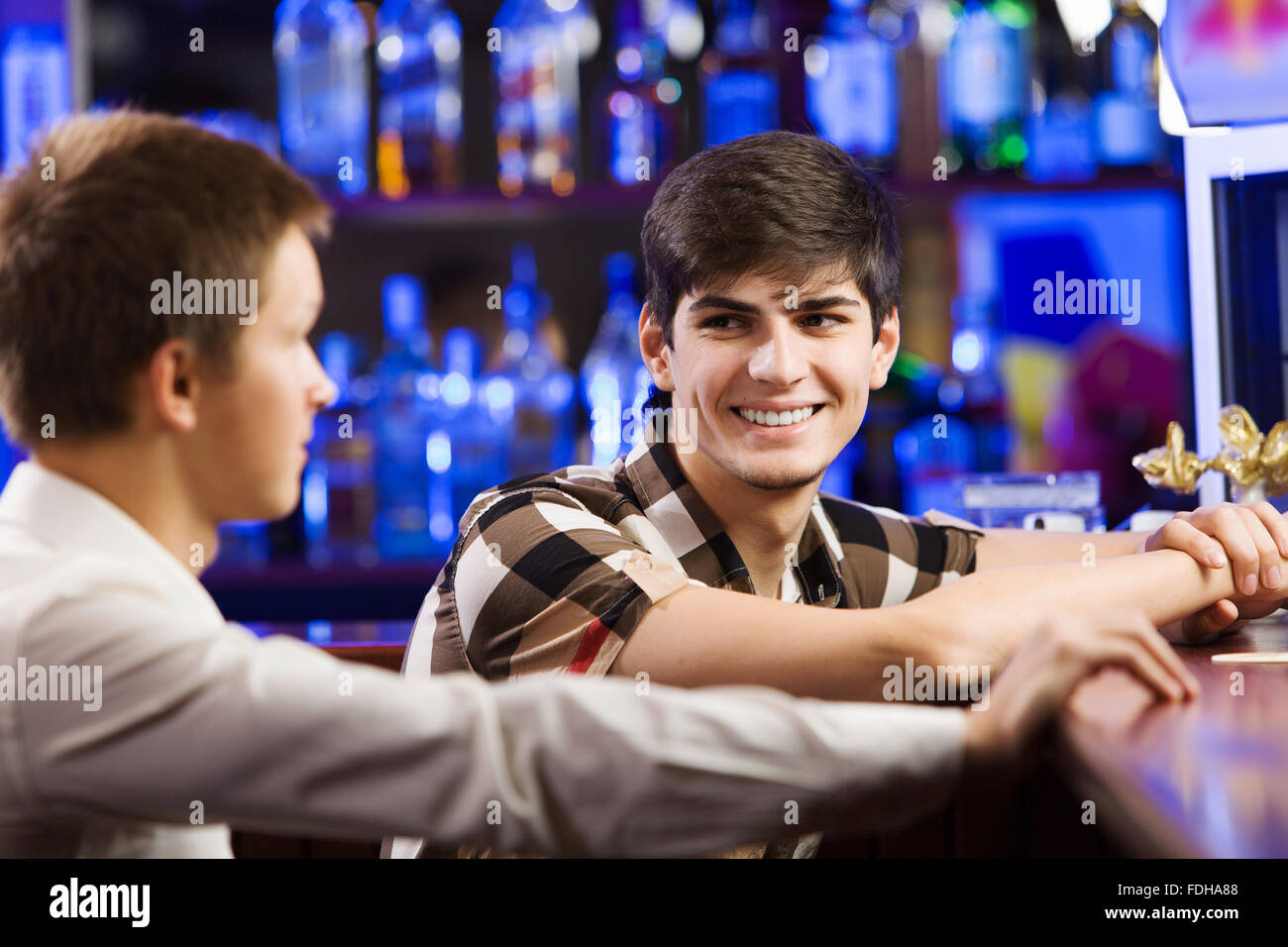 Two young men sitting at bar and talking Stock Photo - Alamy