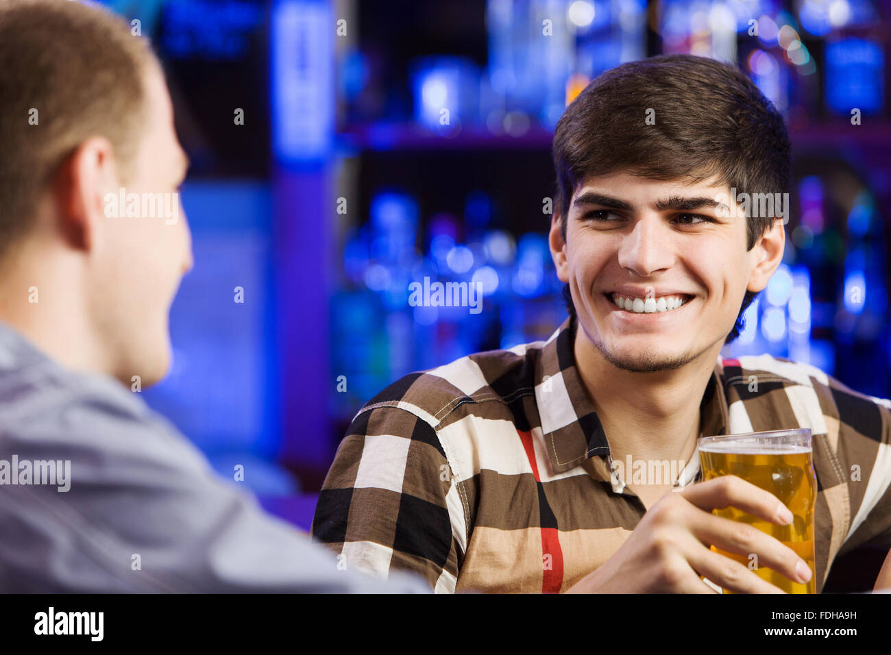Two young men sitting at bar and talking Stock Photo - Alamy