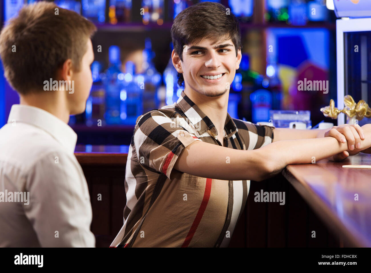 Two young men sitting at bar and talking Stock Photo - Alamy