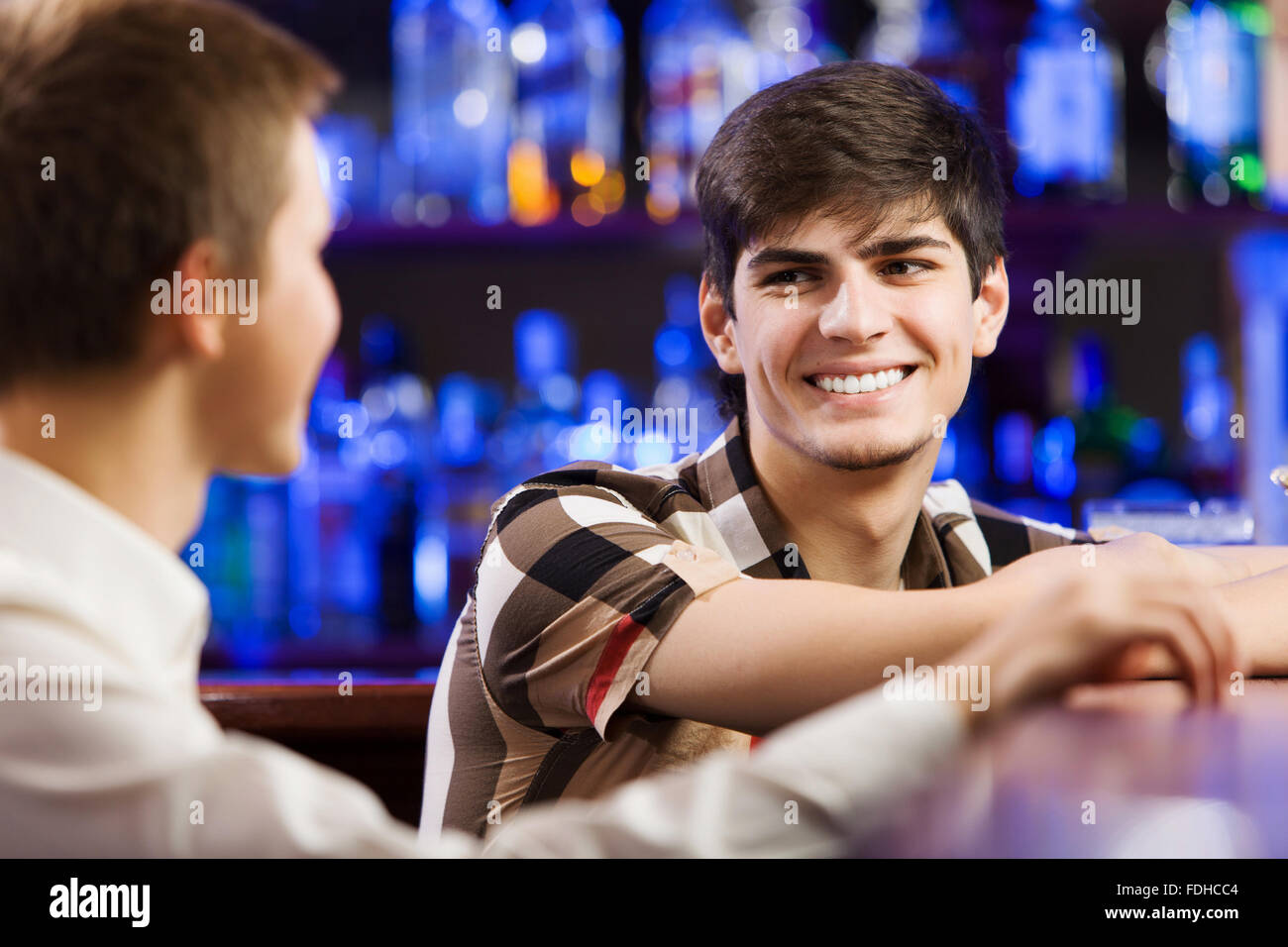 Two young men sitting at bar and talking Stock Photo - Alamy