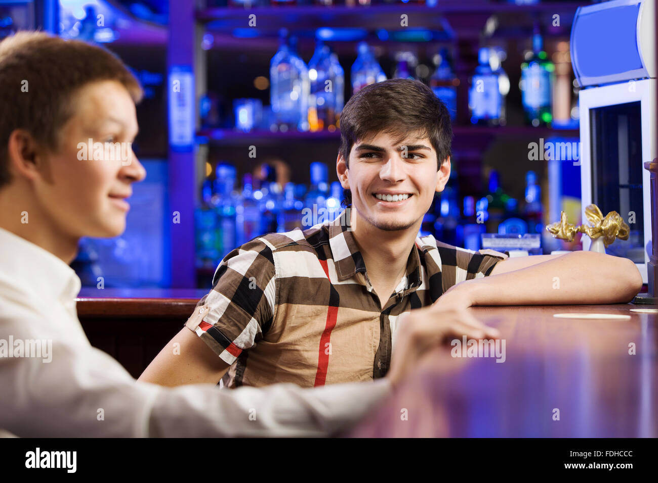 Two young men sitting at bar and talking Stock Photo - Alamy
