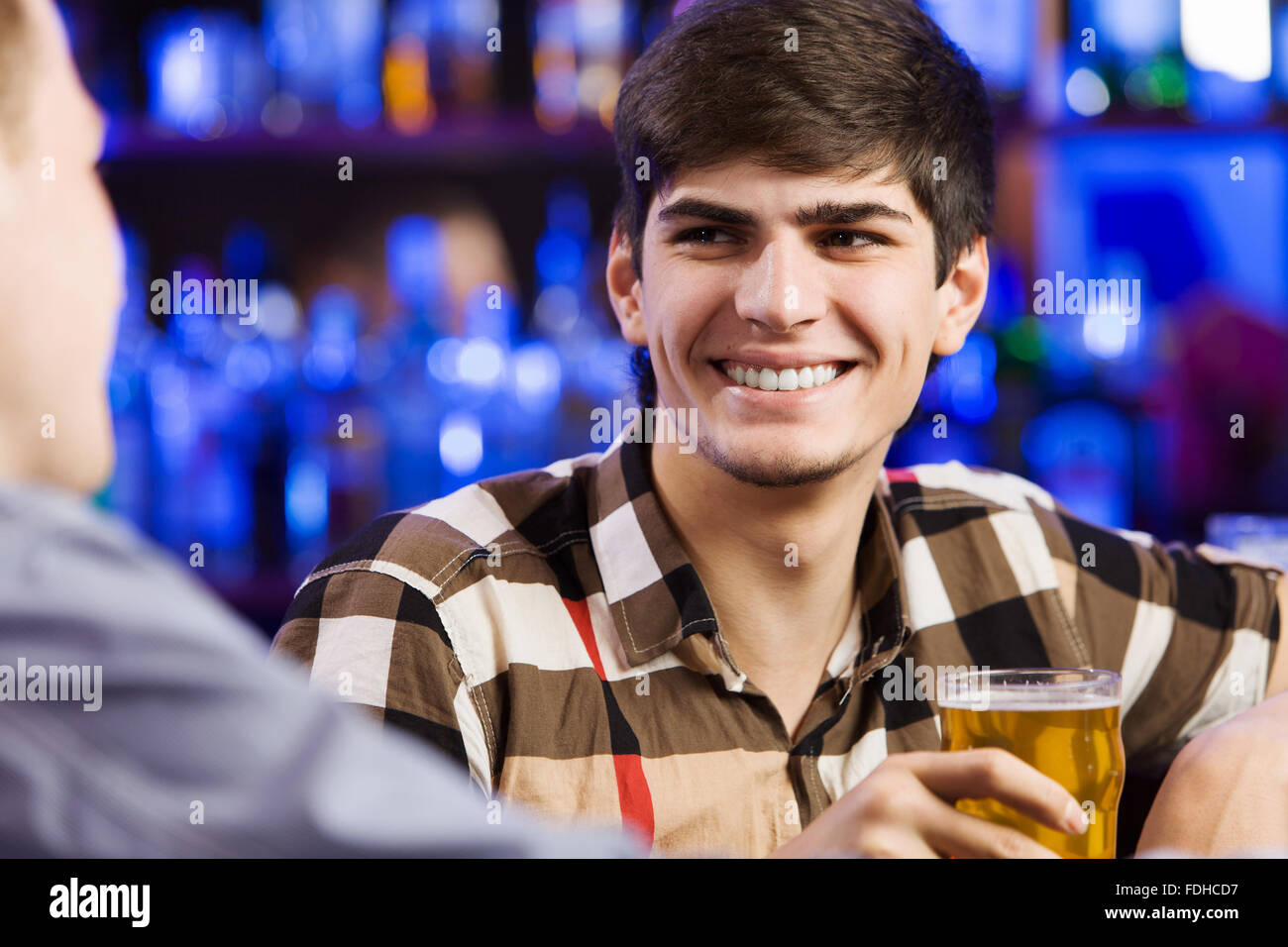 Two young men sitting at bar and talking Stock Photo - Alamy