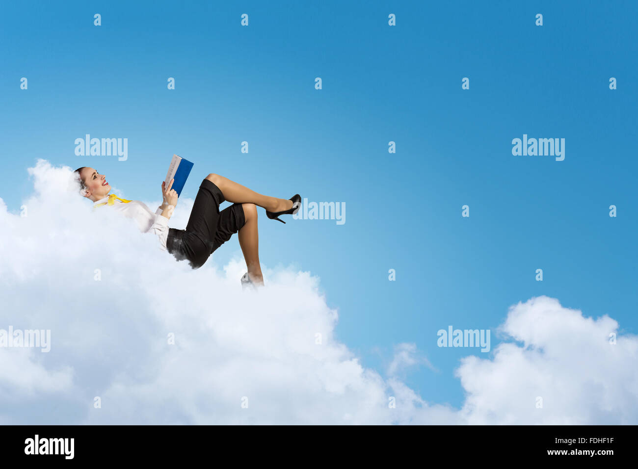 Image of businesswoman lying on clouds with book Stock Photo - Alamy