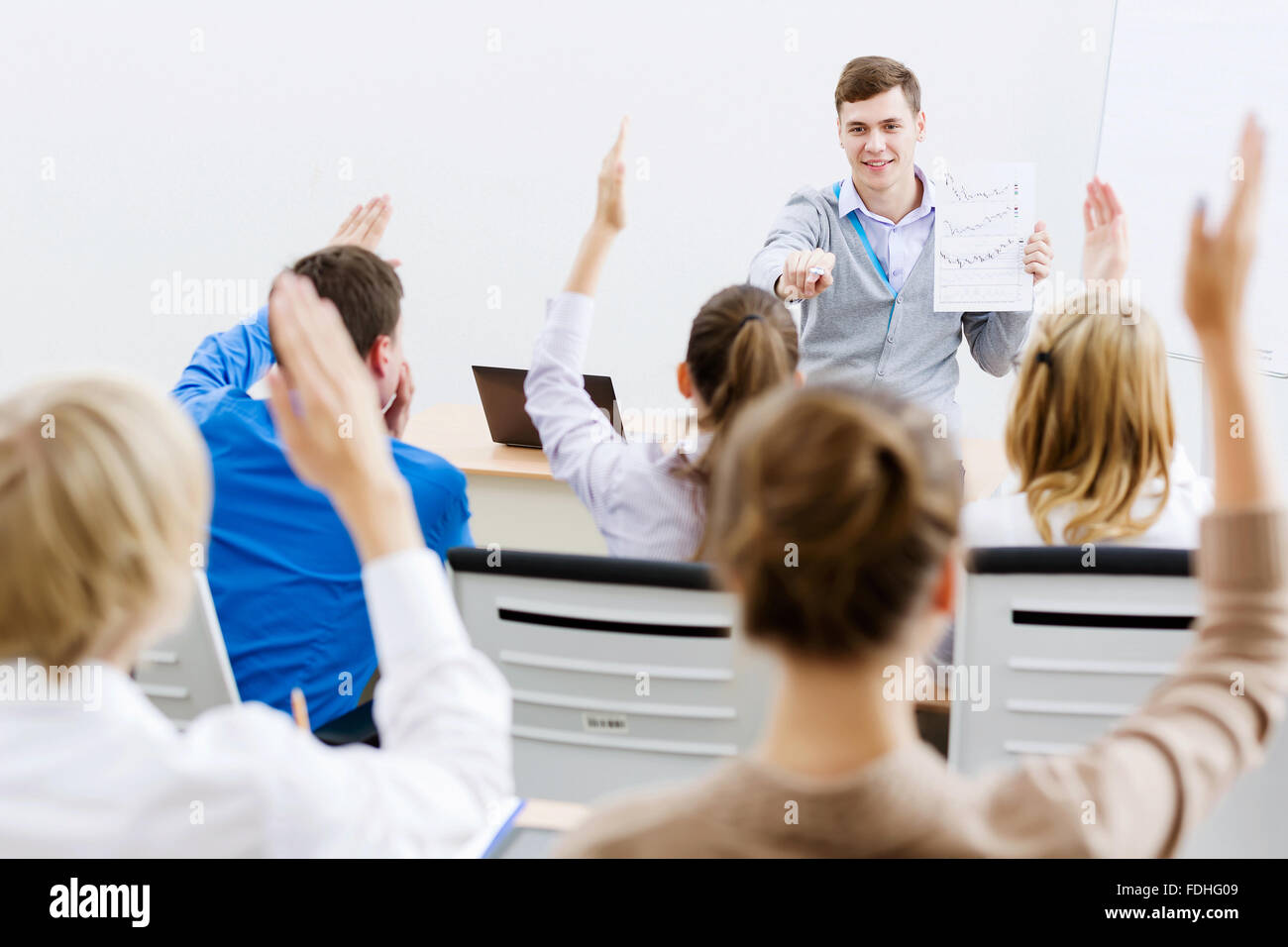 Young teacher in classroom standing in front of class Stock Photo - Alamy