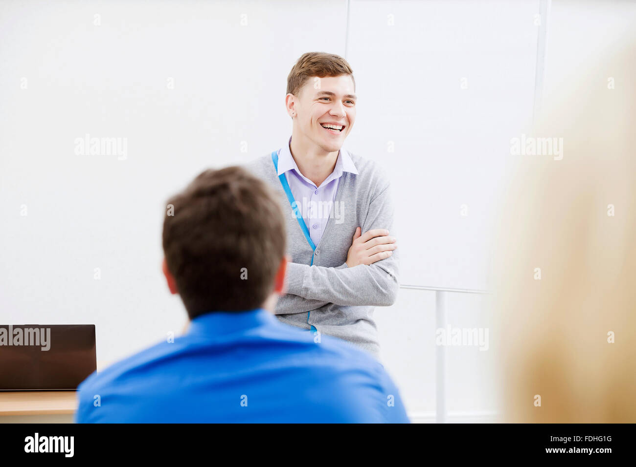 Young teacher in classroom standing in front of class Stock Photo - Alamy