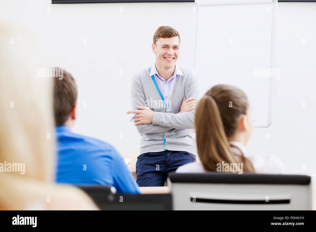 Young teacher in classroom standing in front of class Stock Photo - Alamy
