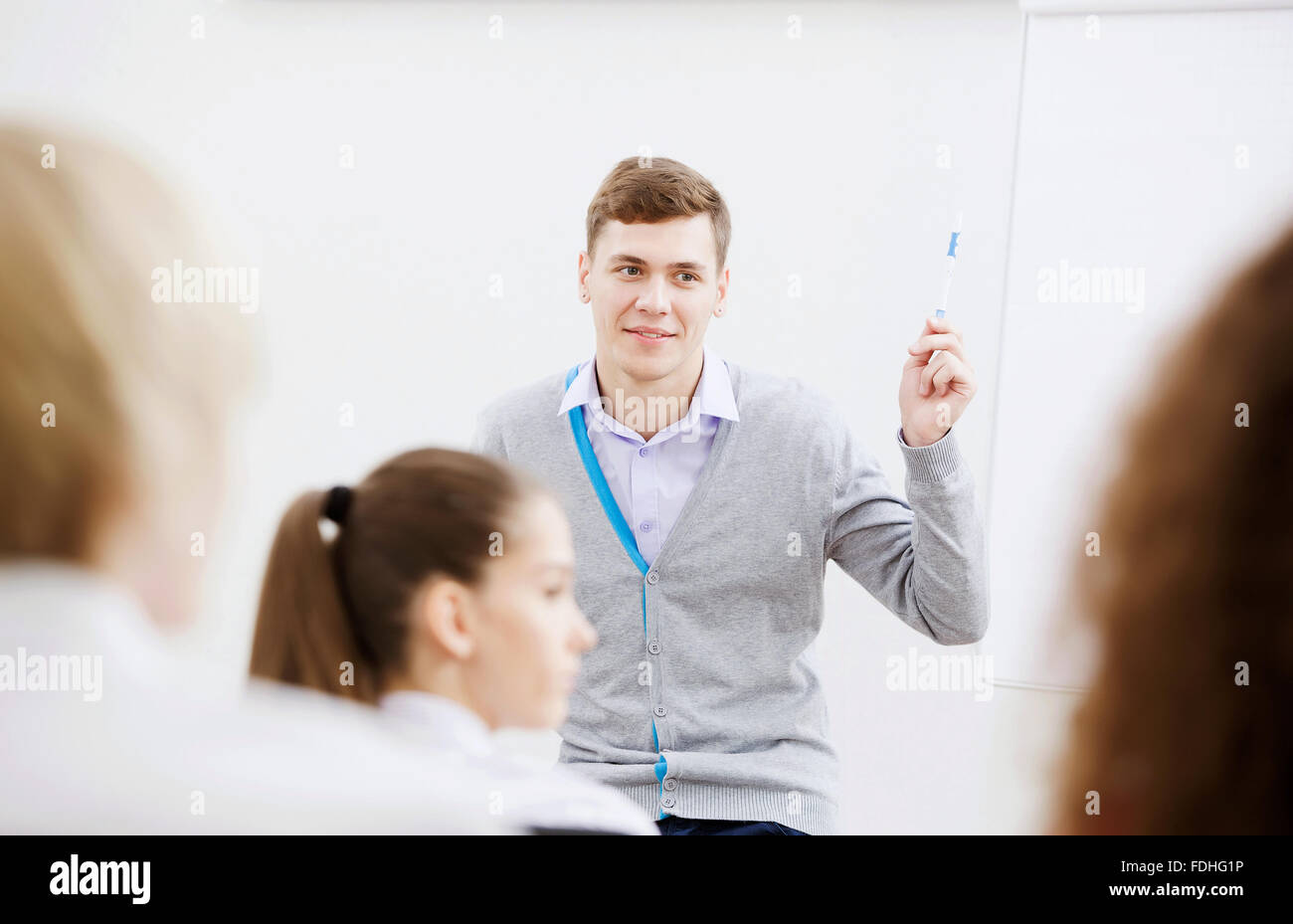 Young teacher in classroom standing in front of class Stock Photo - Alamy