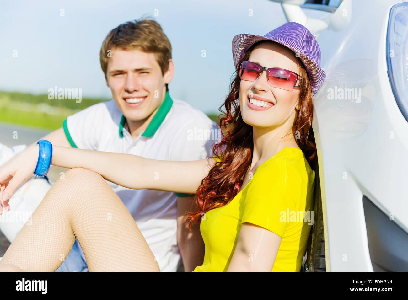 Young people sitting near car aside of road Stock Photo - Alamy
