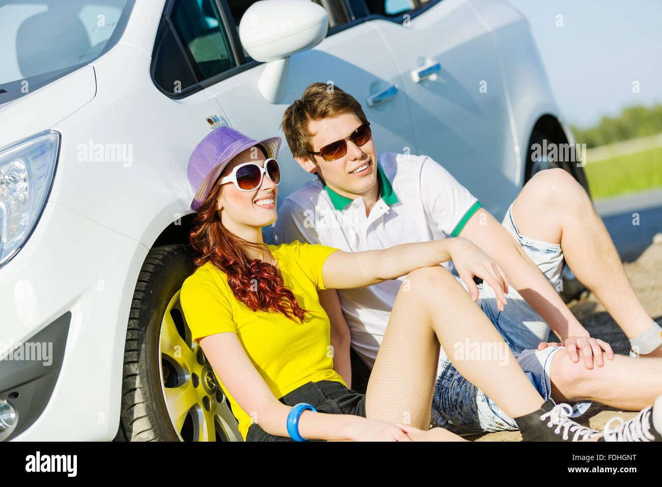 Young people sitting near car aside of road Stock Photo - Alamy
